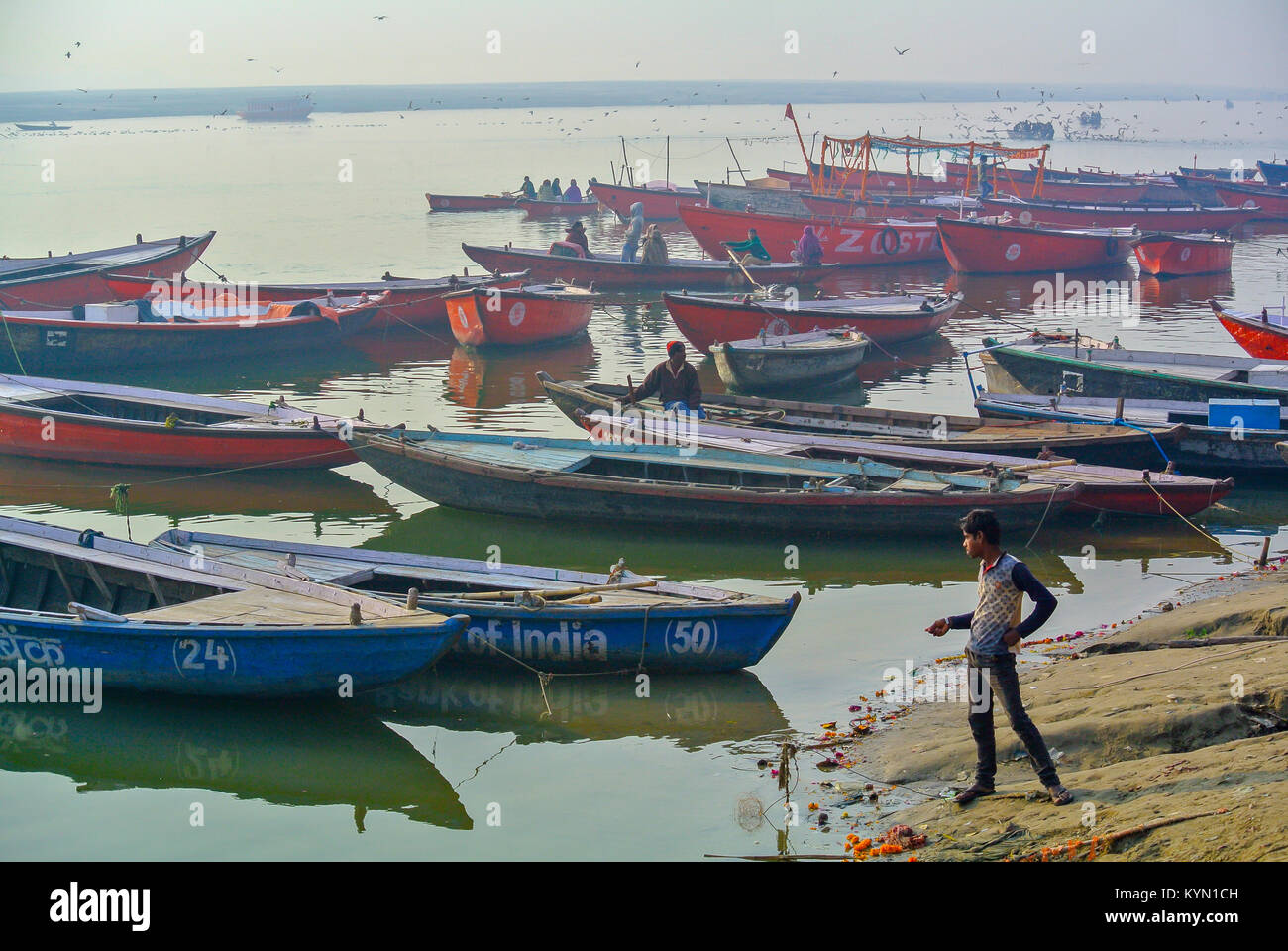 Varanasi, Uttar Pradesh, India, An indian boy with boats on the ganges ...