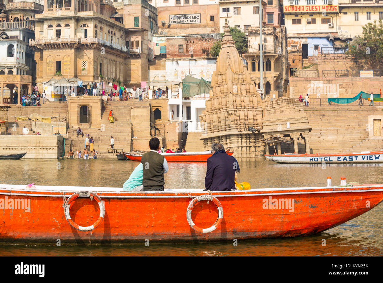 Varanasi, Uttar Pradesh, India, An orange boat with two indian men on ...