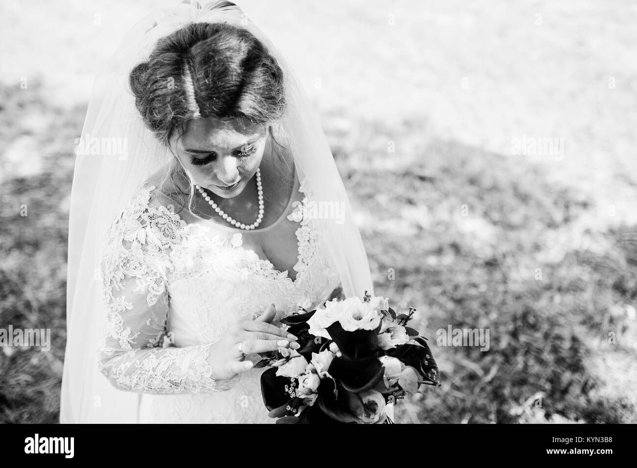 Lonely bride posing in her white dress on her own in the park. Black ...