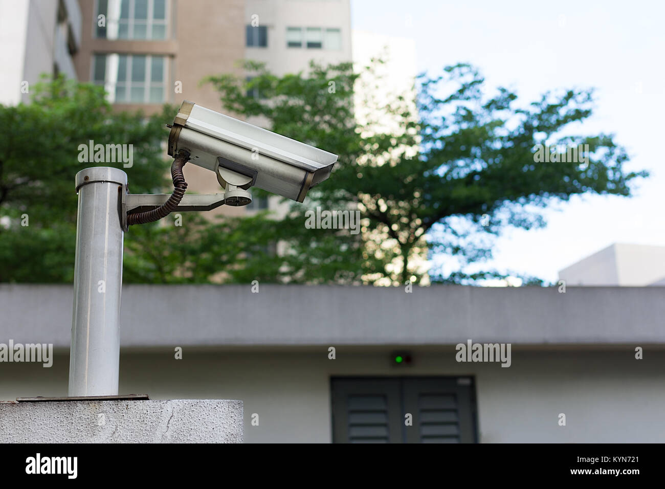 Grey CCTV camera mounted on top of a wall watching over an area Stock ...