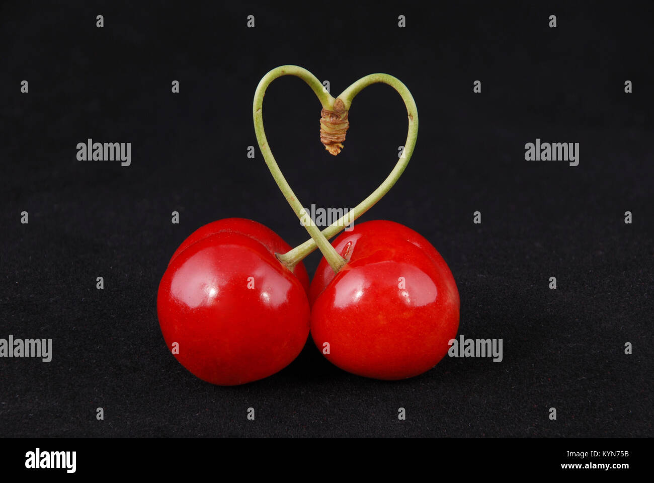 Pair of sweet cherry fruits with heart shaped stem isolated on black ...