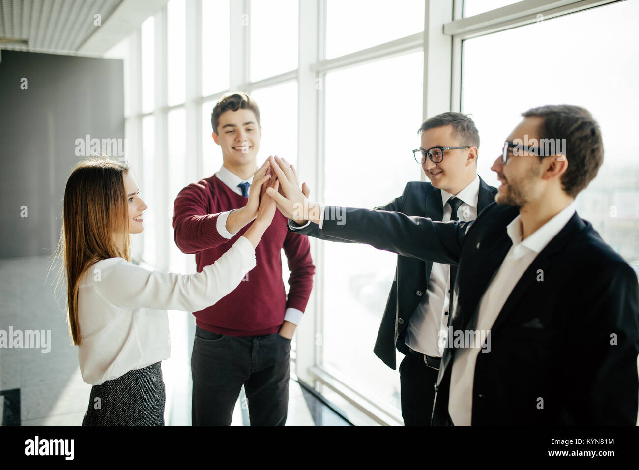 The four business people greeting with a high five Stock Photo - Alamy