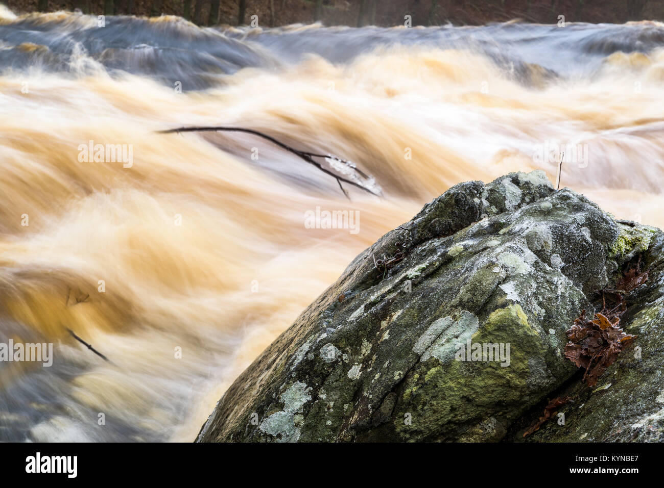 Frost and ice on granite boulder with whitewater rapid in background ...