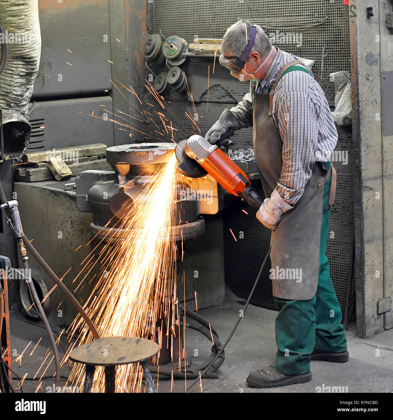 Workers in a foundry grind castings with a grinding machine - Heavy ...