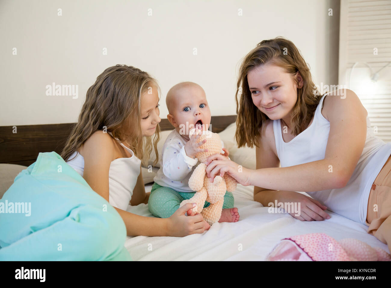 three sisters baby girl children in the morning on the bed in the ...