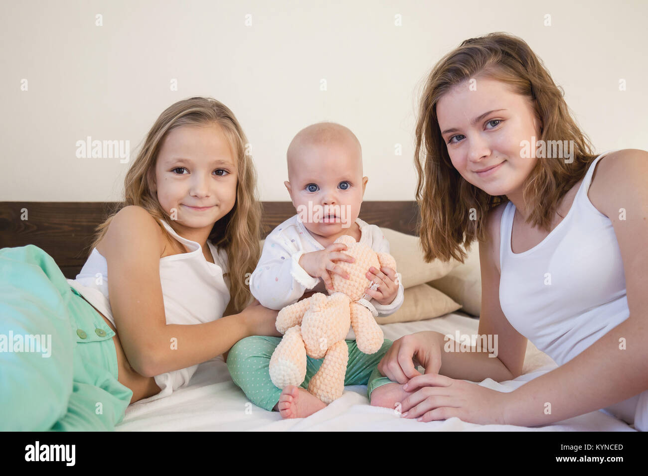 three sisters baby girl children in the morning on the bed in the ...