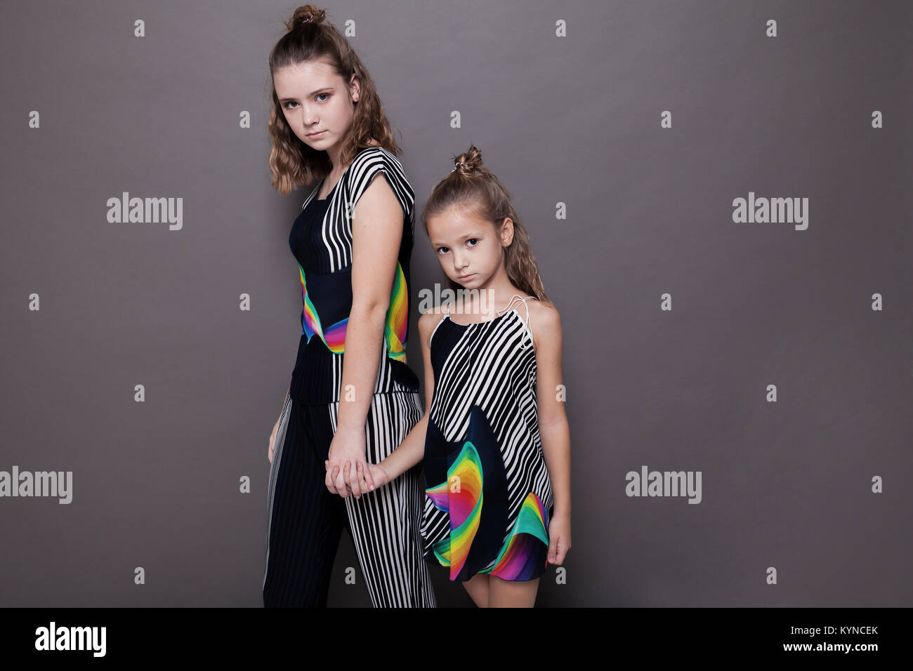 two girls sisters side by side on a grey background Stock Photo - Alamy
