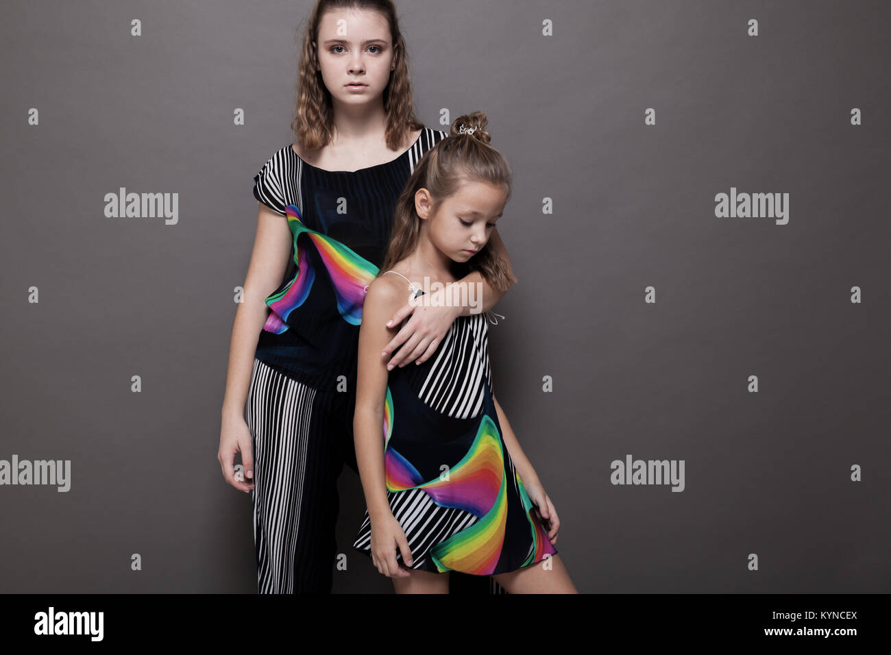 two girls sisters side by side on a grey background Stock Photo - Alamy