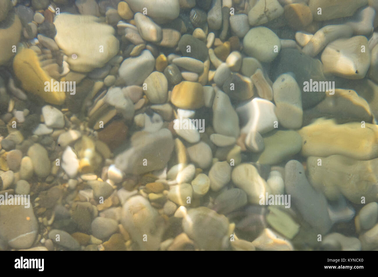sea pebble beach with multicoloured stones, transparent waves with foam ...