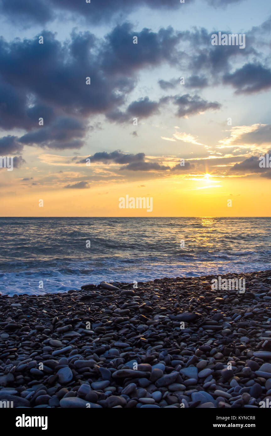 Summer sea sunset on the pebble beach, the sun, waves and clouds ...