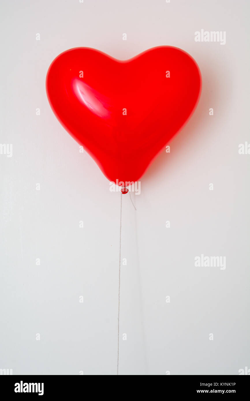 Red heart shaped balloon on a string isolated on white Stock Photo - Alamy