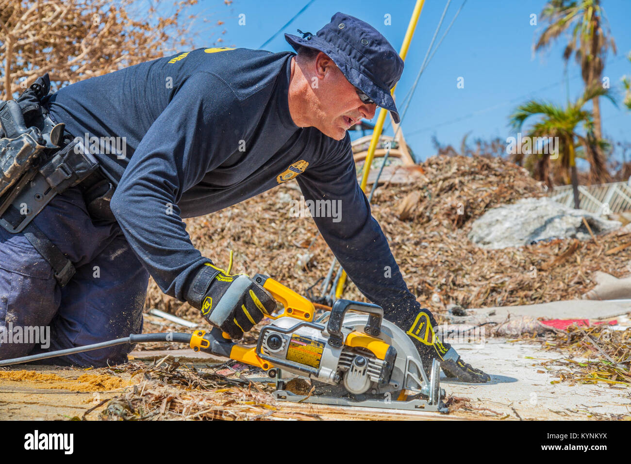 A CBP Disaster Assistance Recovery Team member is seen cutting up ...