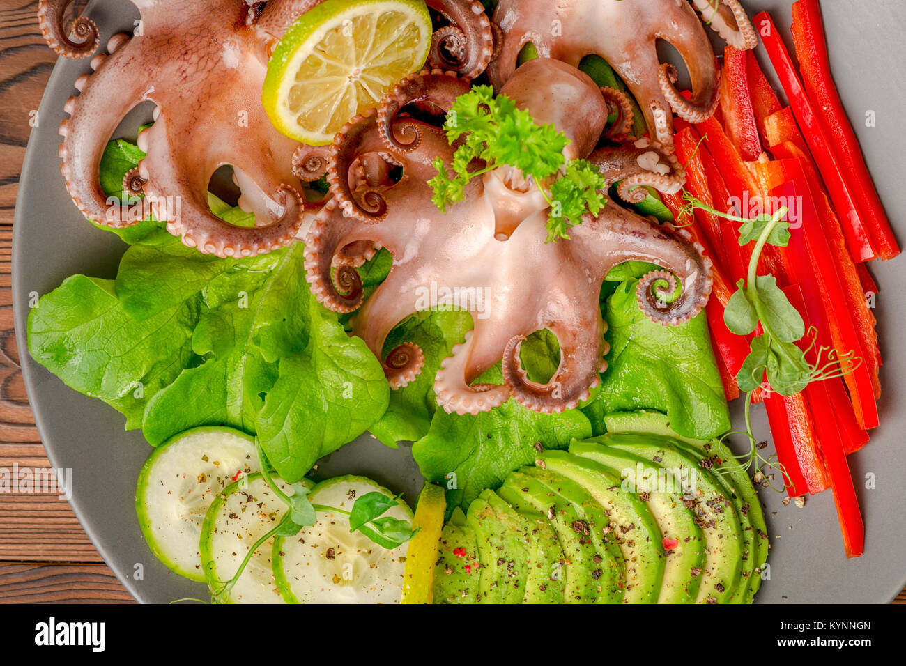 top down of octopus served with sliced avocado, lettuce, red pepper ...