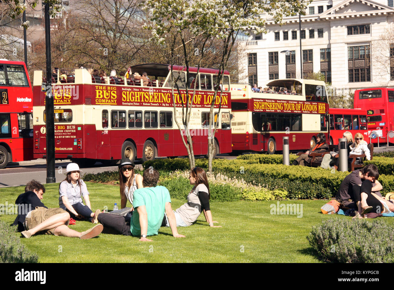 Young people sat on the grass talking in a central London garden with ...