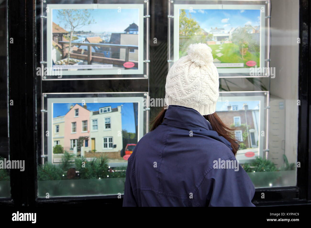 Woman looking in the window of an estate agent, or real estate office ...