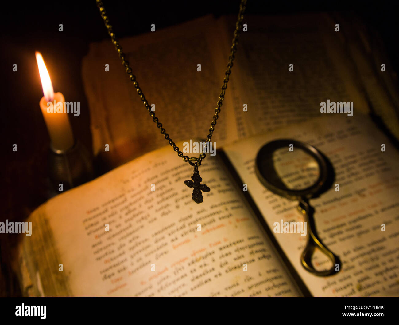 The cross hangs over a prayer book with a magnifying glass at a burning ...