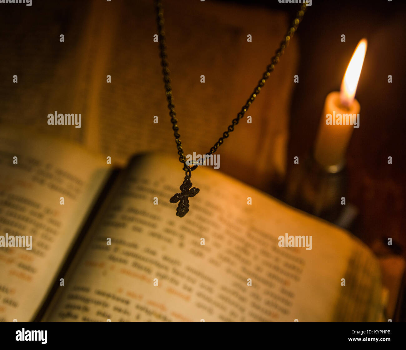 The cross hangs over a prayer book with a magnifying glass at a burning ...