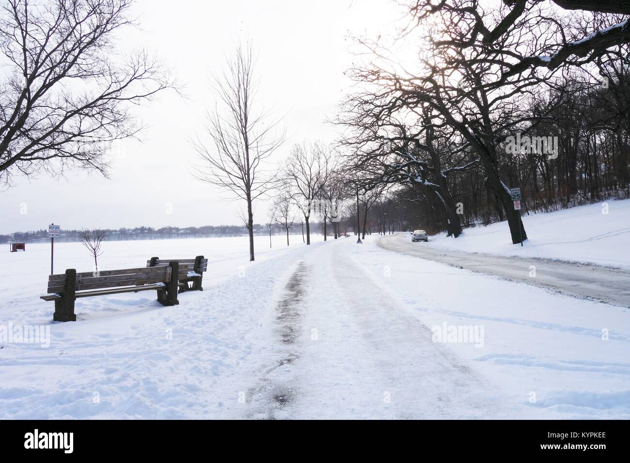 An isolated snowy walking path next to Lake Harriet in Minneapolis ...