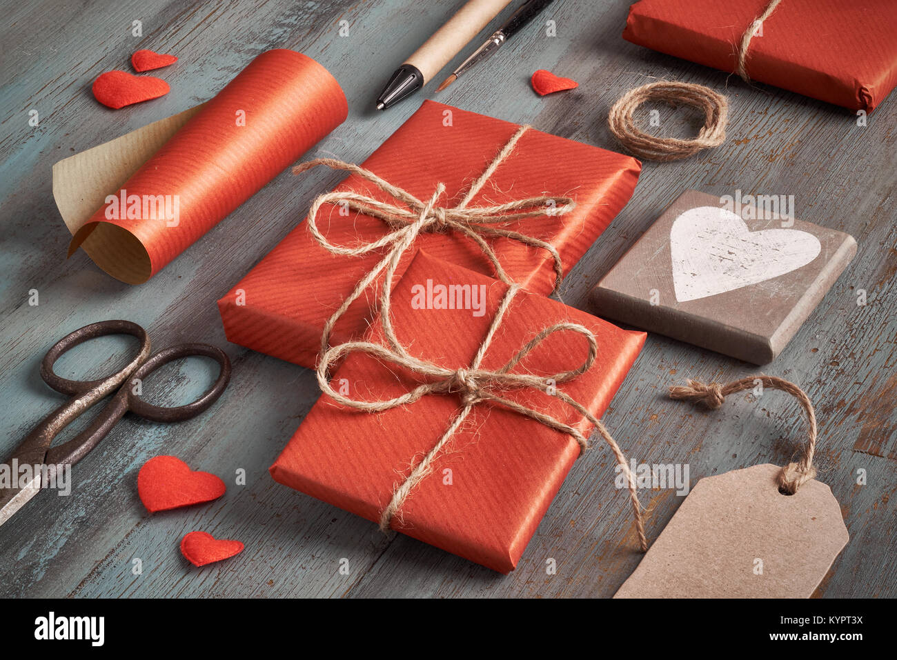 Packed present, wrapping paper, labels, scissors and decorative hearts ...