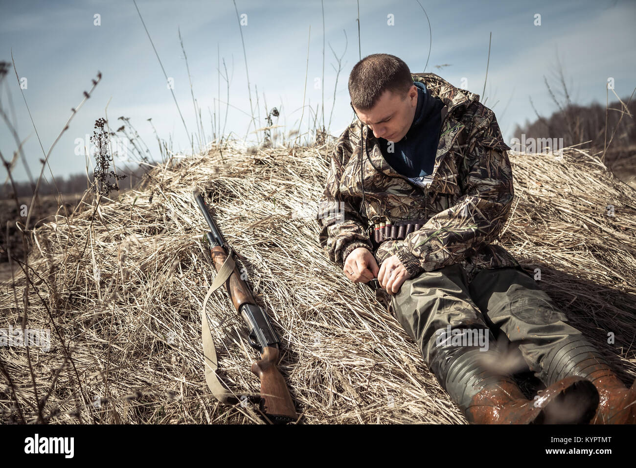 Hunter man preparing for hunting in rural field with shotgun during ...
