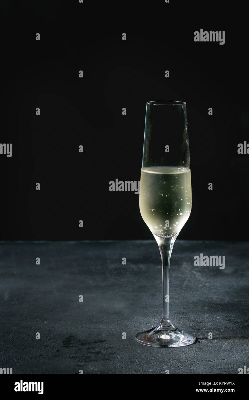One glass of white champagne over dark texture background. Copy space ...
