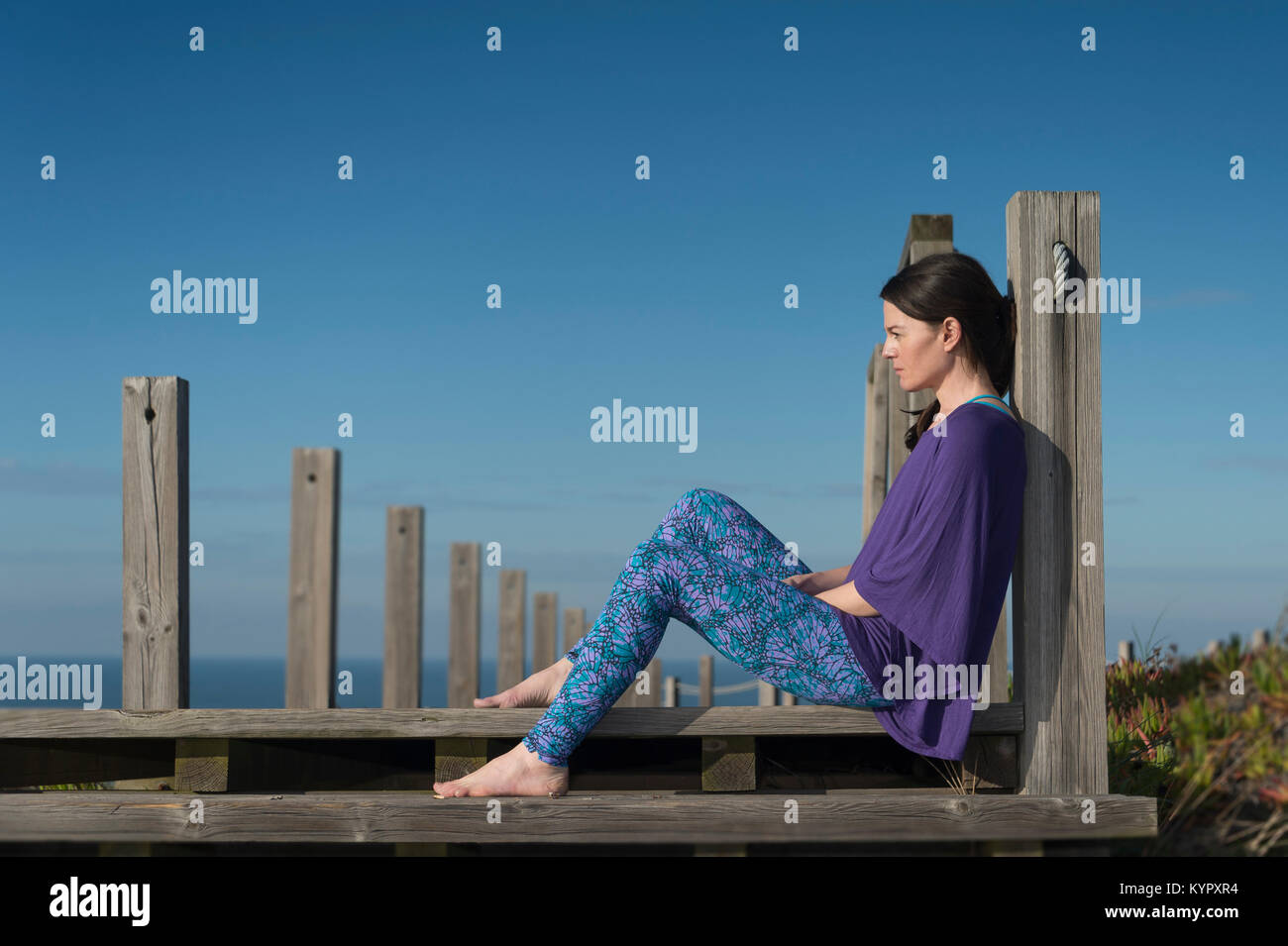 woman sitting on wooden steps by the sea, thinking and relaxing in the ...