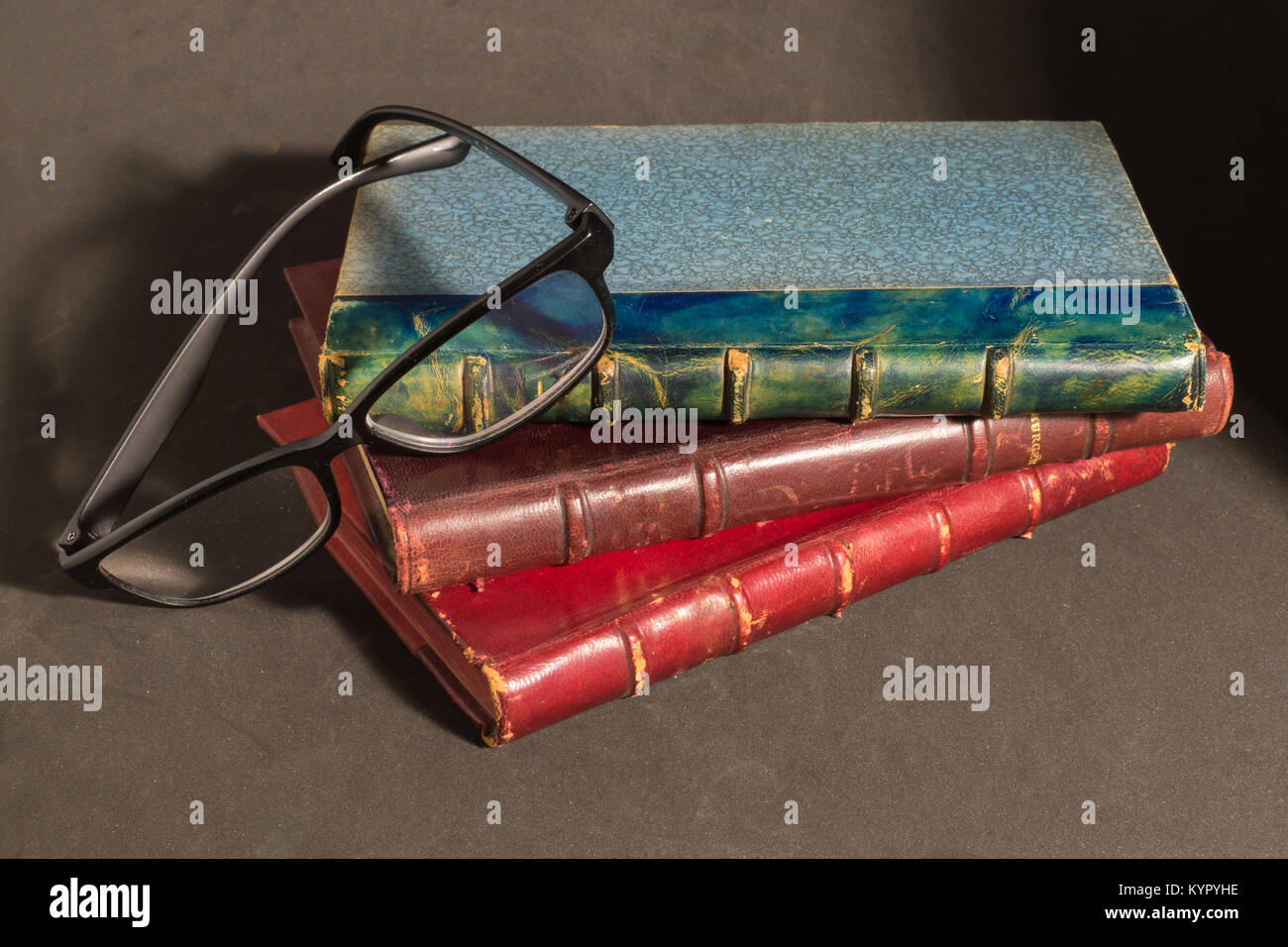 Vintage red, brown and green poetry books with a black glass on black ...