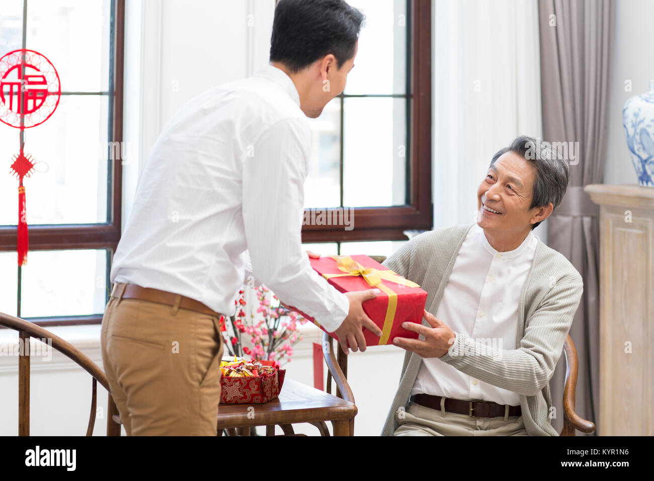 Son giving gift to his father during Chinese New Year Stock Photo - Alamy