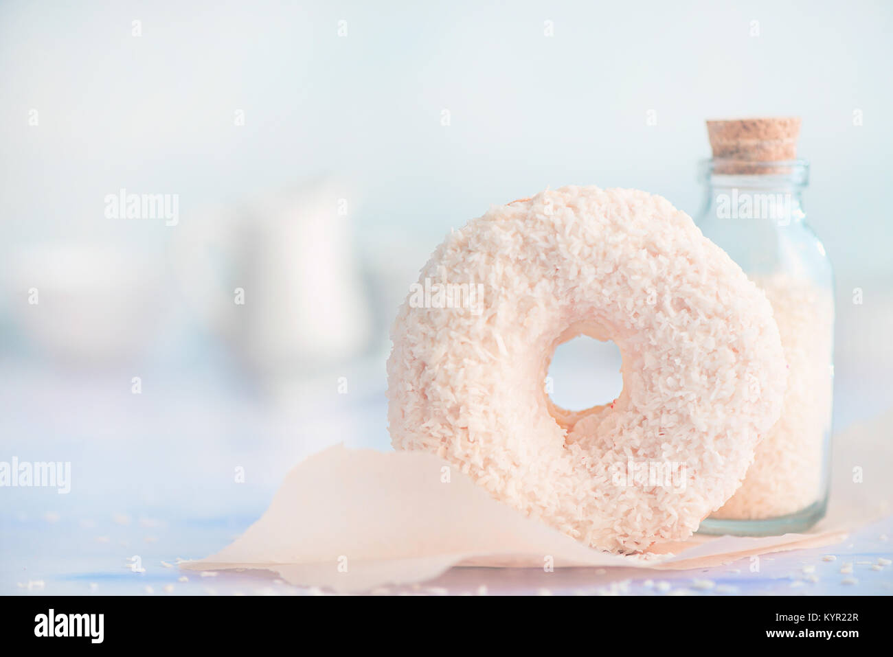 Coconut cream filled white donut with coconut topping on a light ...