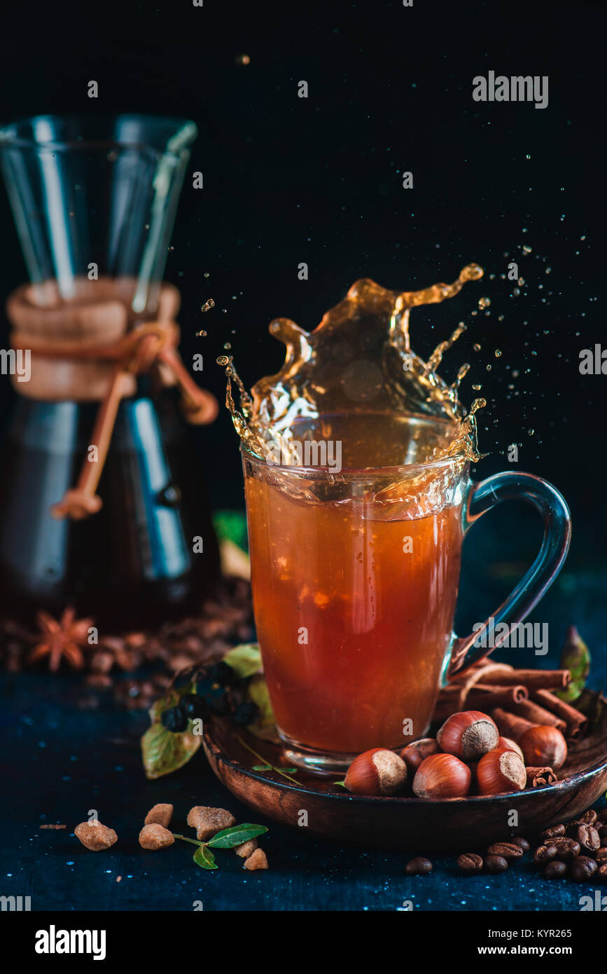 Coffee splash in a tall latte glass with hourglass coffee maker, spices ...