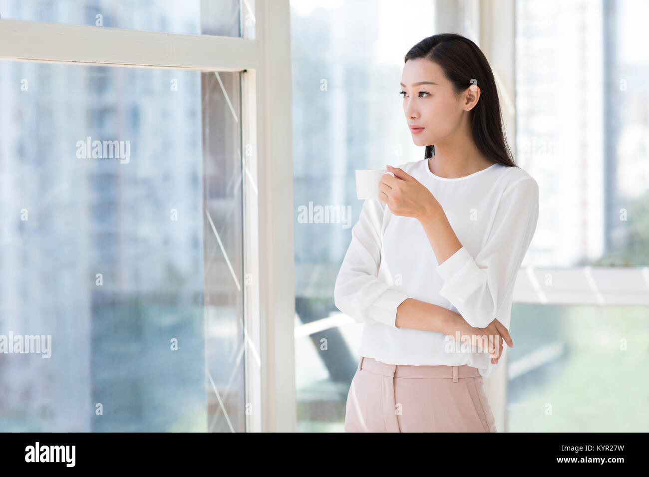 Young businesswoman drinking coffee in office Stock Photo - Alamy