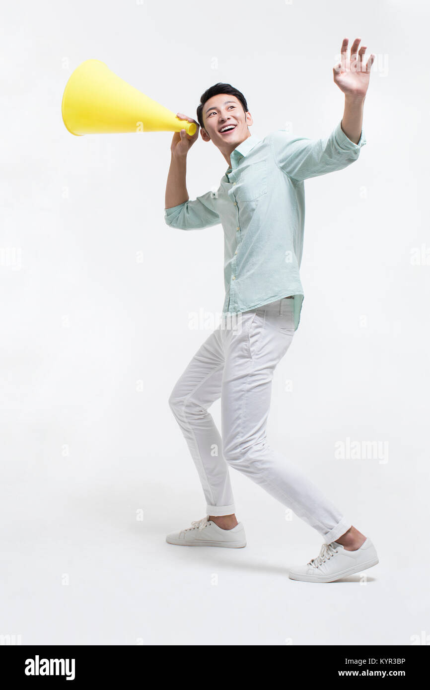 Young man listening through megaphone Stock Photo - Alamy