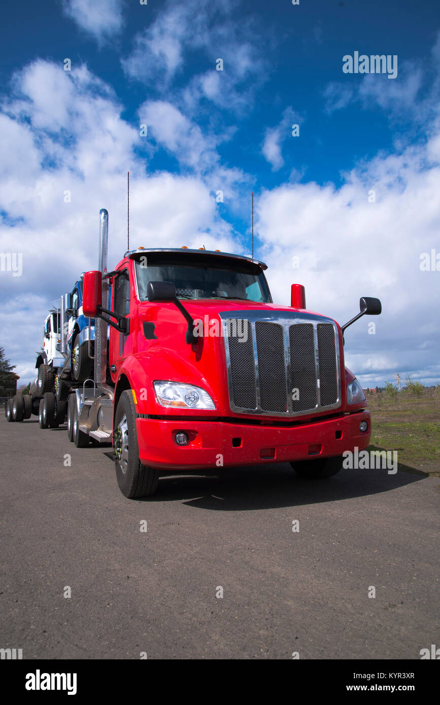 A powerful modern big rig red semi truck carries other articulated ...