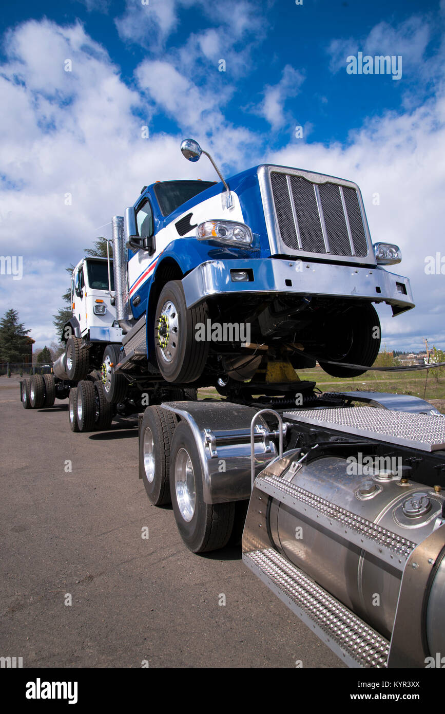A powerful modern big rig semi truck carries other articulated lorry ...