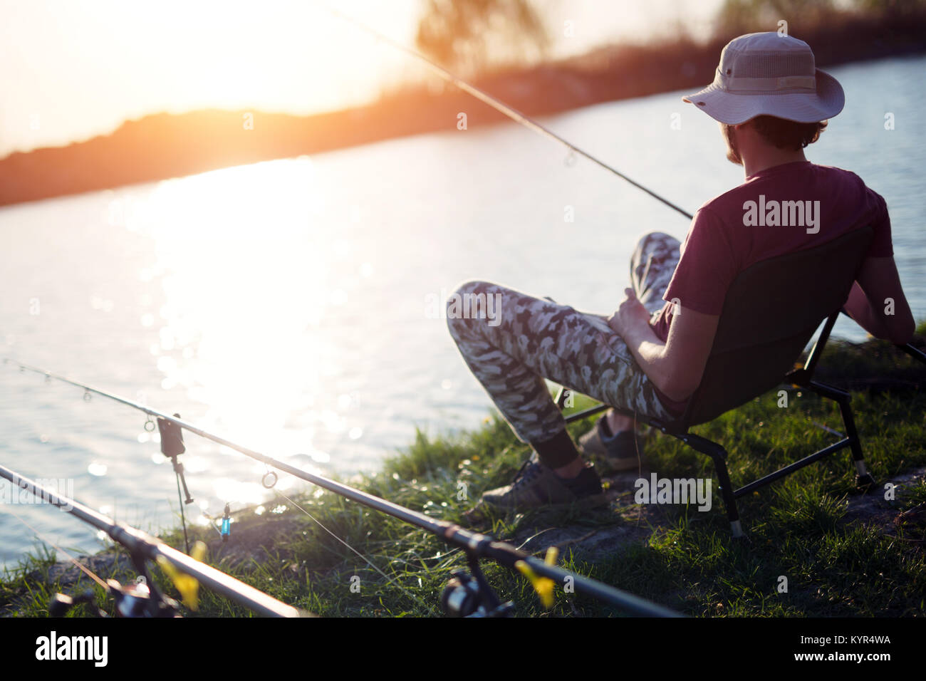Young man fishing on lake at sunset enjoying hobby Stock Photo - Alamy