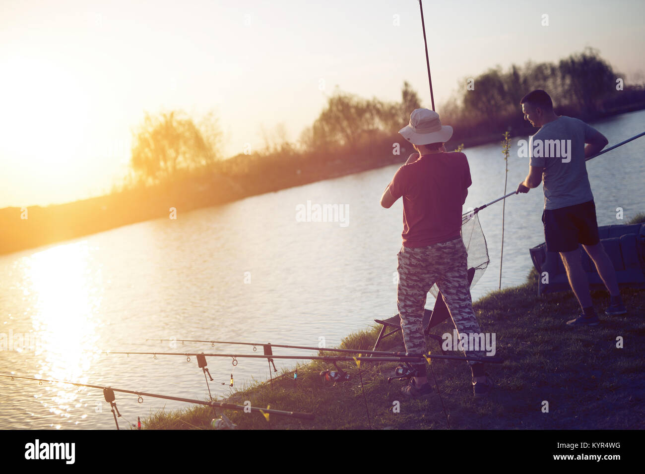 Men fishing in sunset and relaxing while enjoying hobby Stock Photo - Alamy