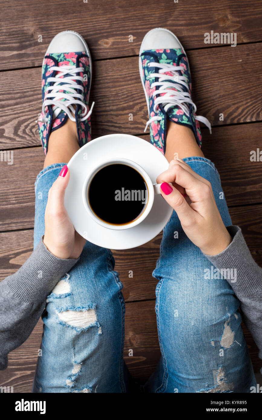Woman drinking coffee while sitting on wooden floor Stock Photo - Alamy