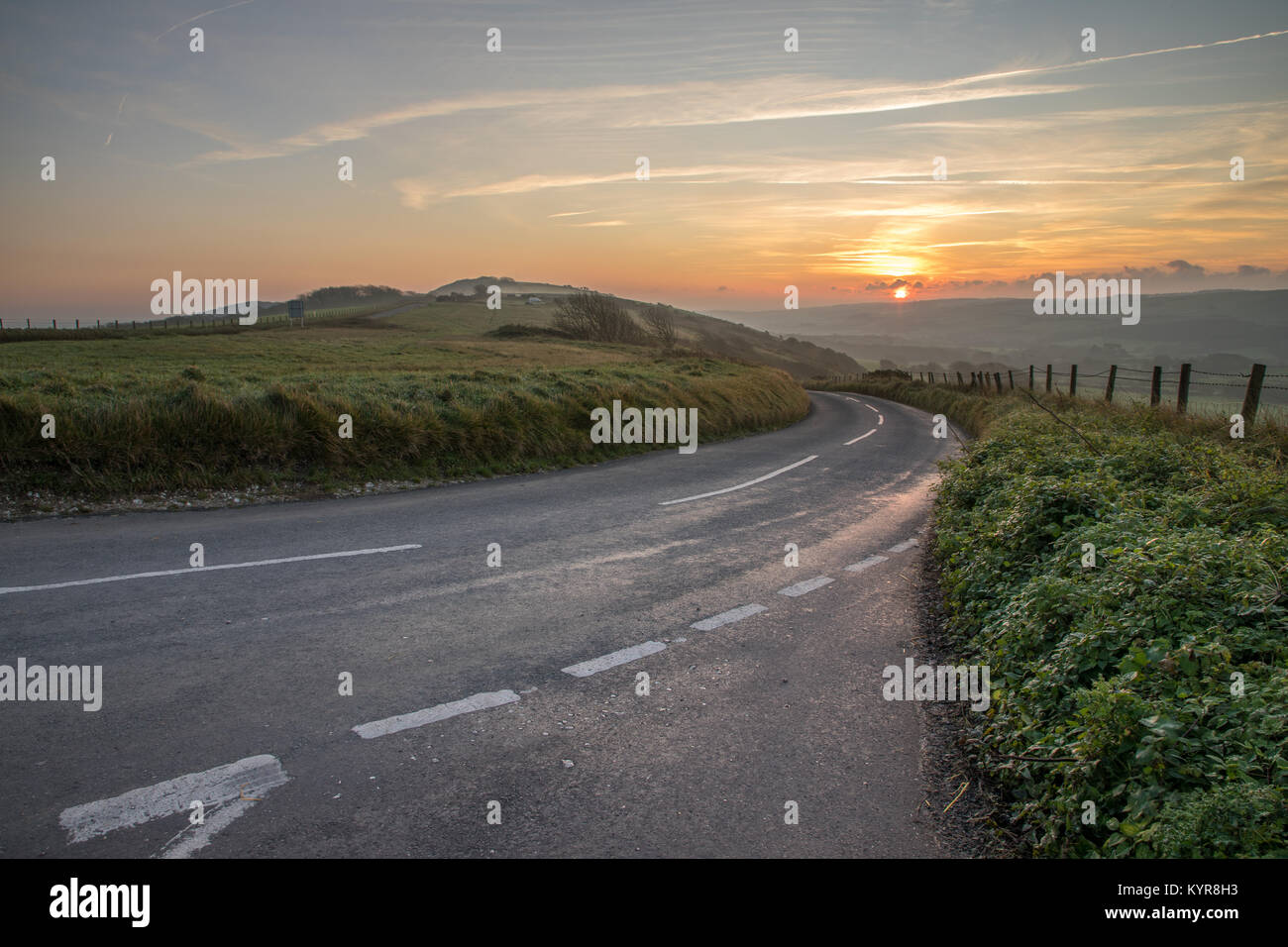 road over hills in mist at sunrise Stock Photo - Alamy