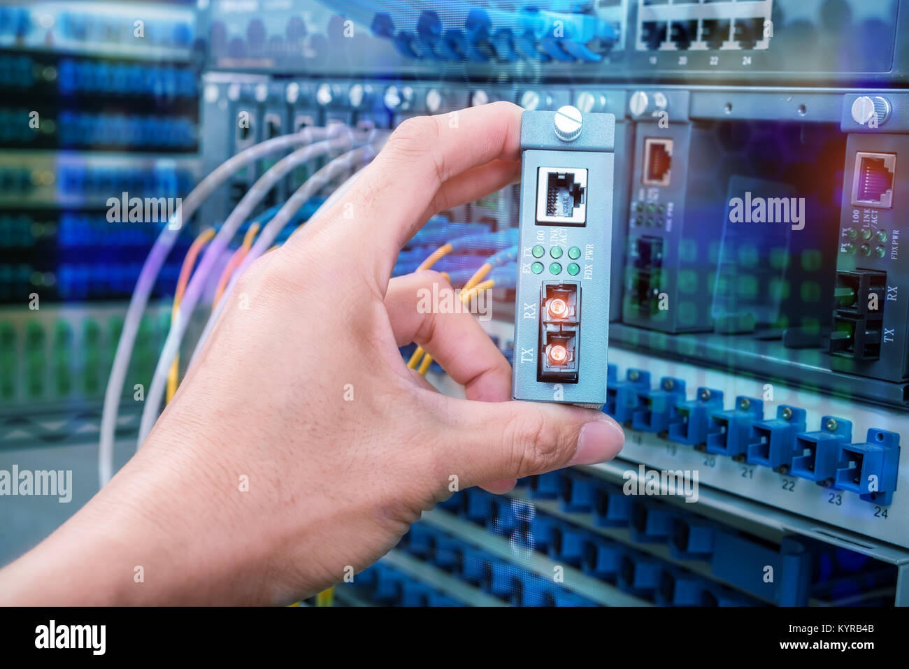 man working in network server room with Fiber Optic cables connected to ...