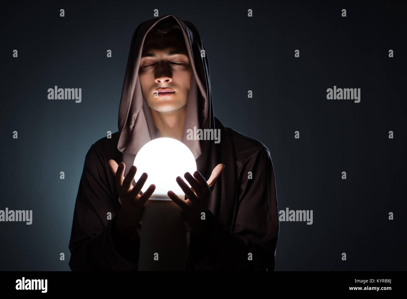Young wizard with crystal ball in dark room Stock Photo - Alamy