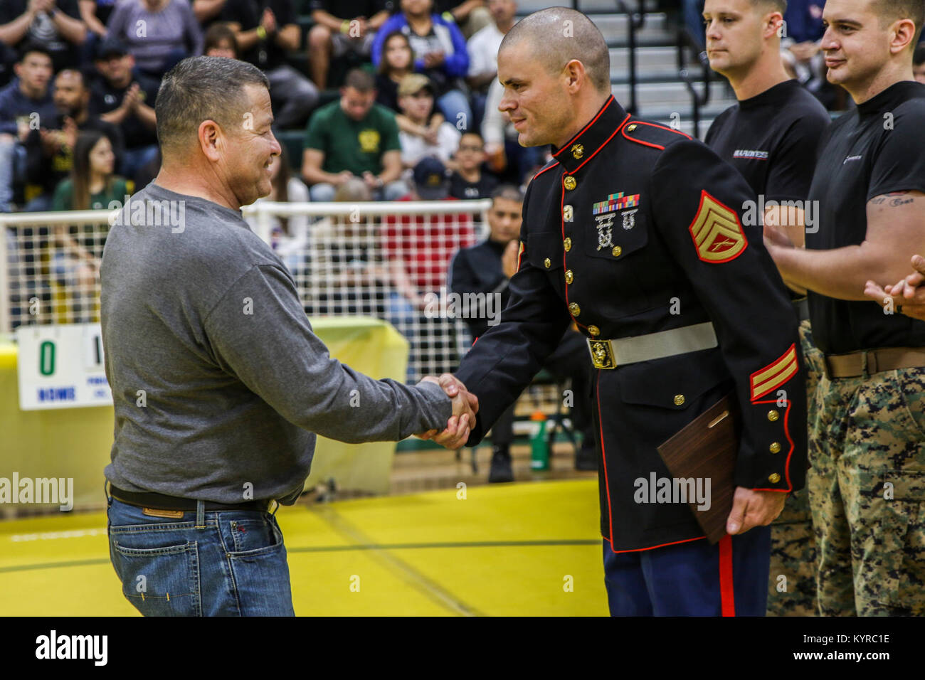 U.S. Marine Staff Sgt. Steven Stone congratulates and presents Richard ...