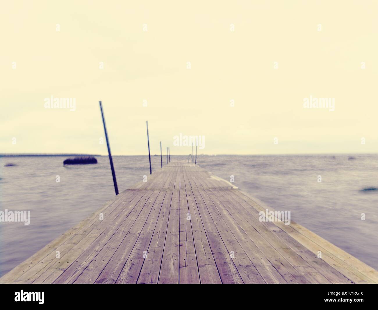 Wet wooden pier in smooth water of sea bay. Old mole anchored with ...