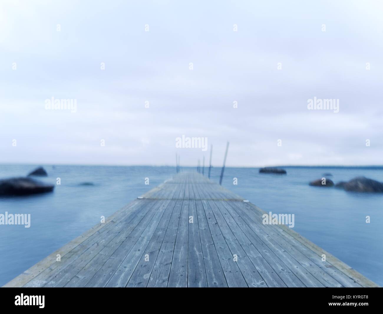 Wet wooden pier in smooth water of sea bay. Old mole anchored with ...