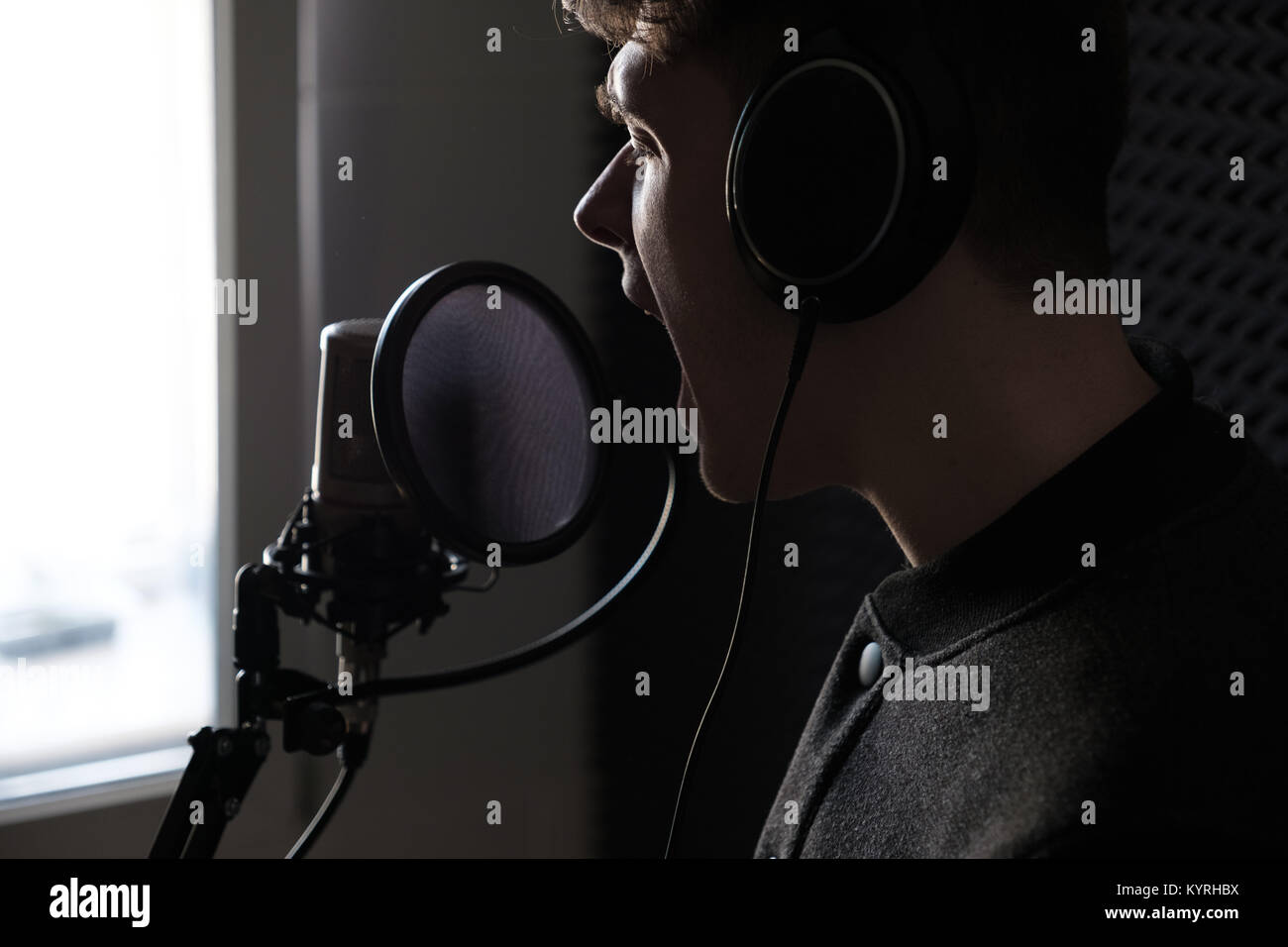 Close-up portrait of a young man singing before a microphone in front ...