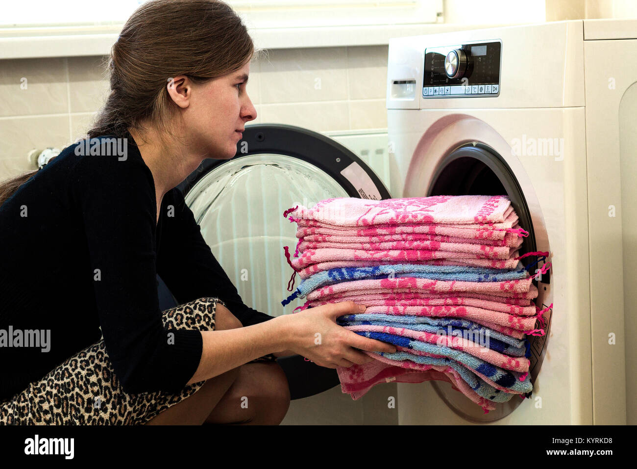 Woman putting laundry into washing machine at home Stock Photo - Alamy