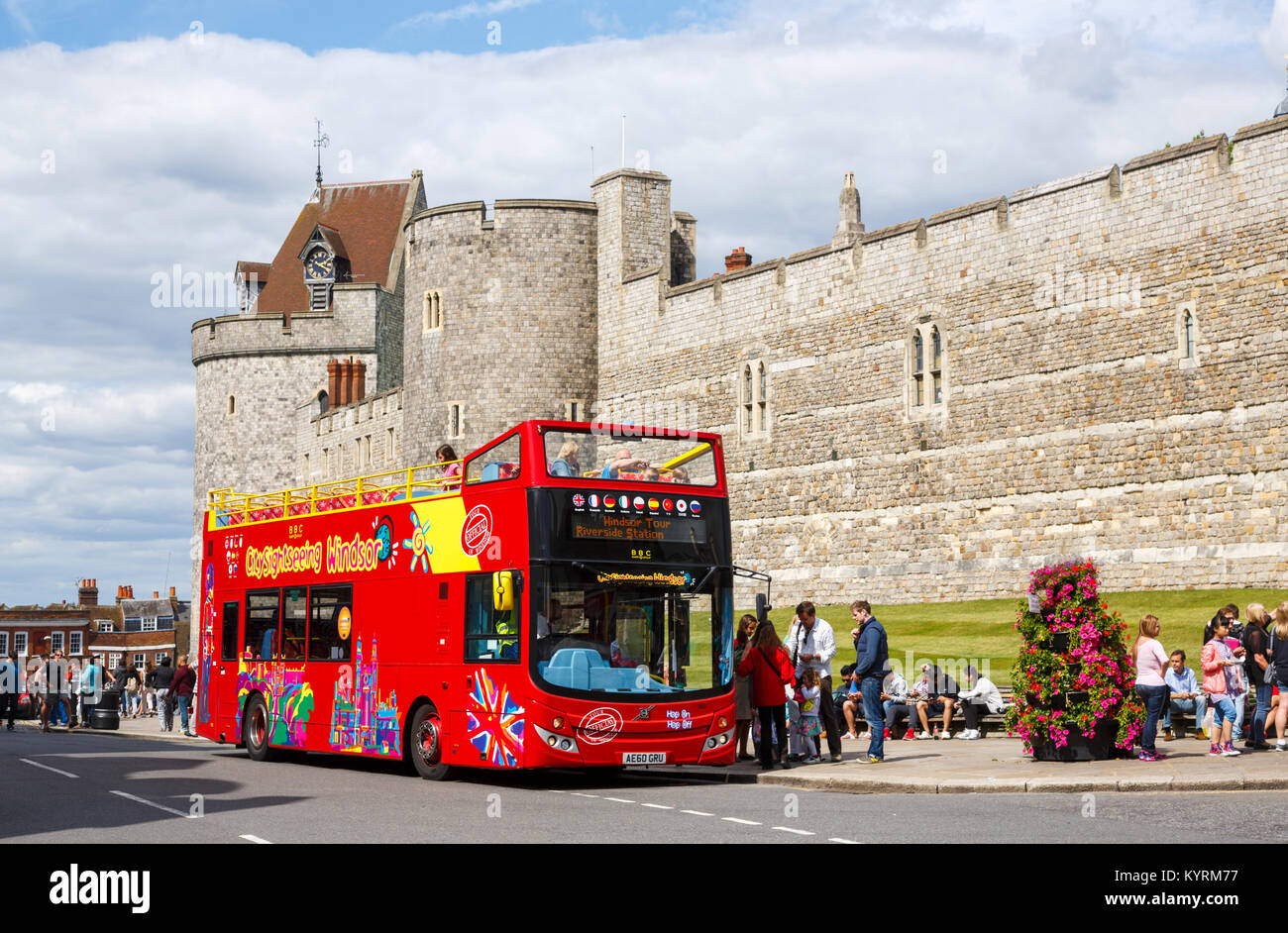 Open-top sightseeing red bus parked outside the walls and tower of ...