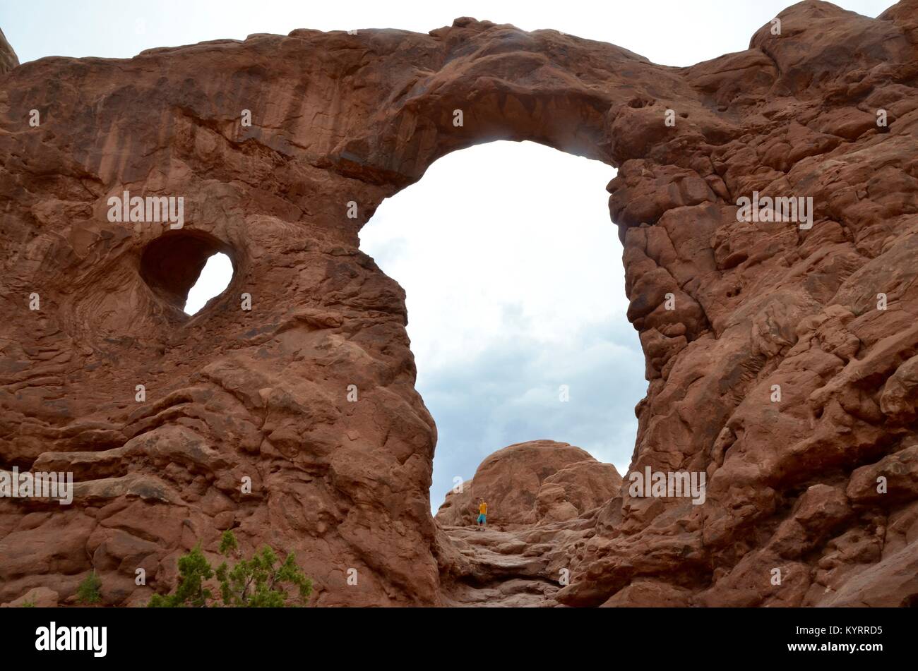 lone boy sits under an south window arch to the arches national park ...