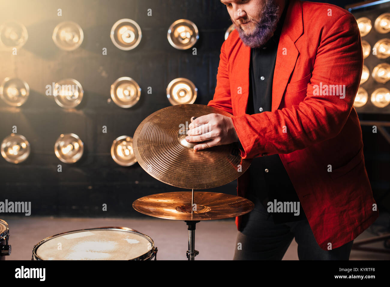 Bearded drummer in red suit on the stage with lights, retro style ...