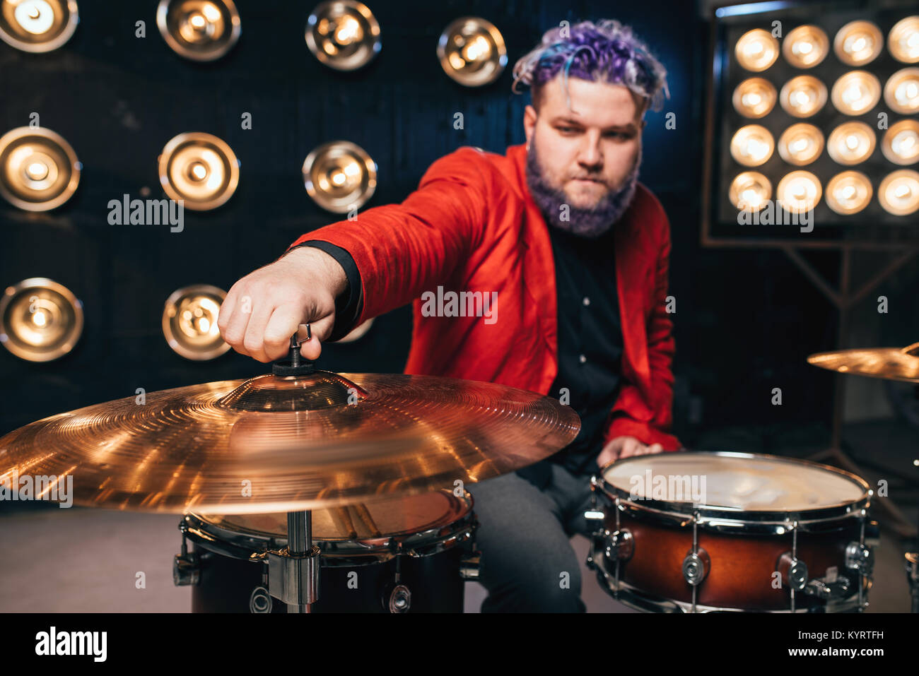 Bearded drummer in red suit on the stage with lights, retro style ...