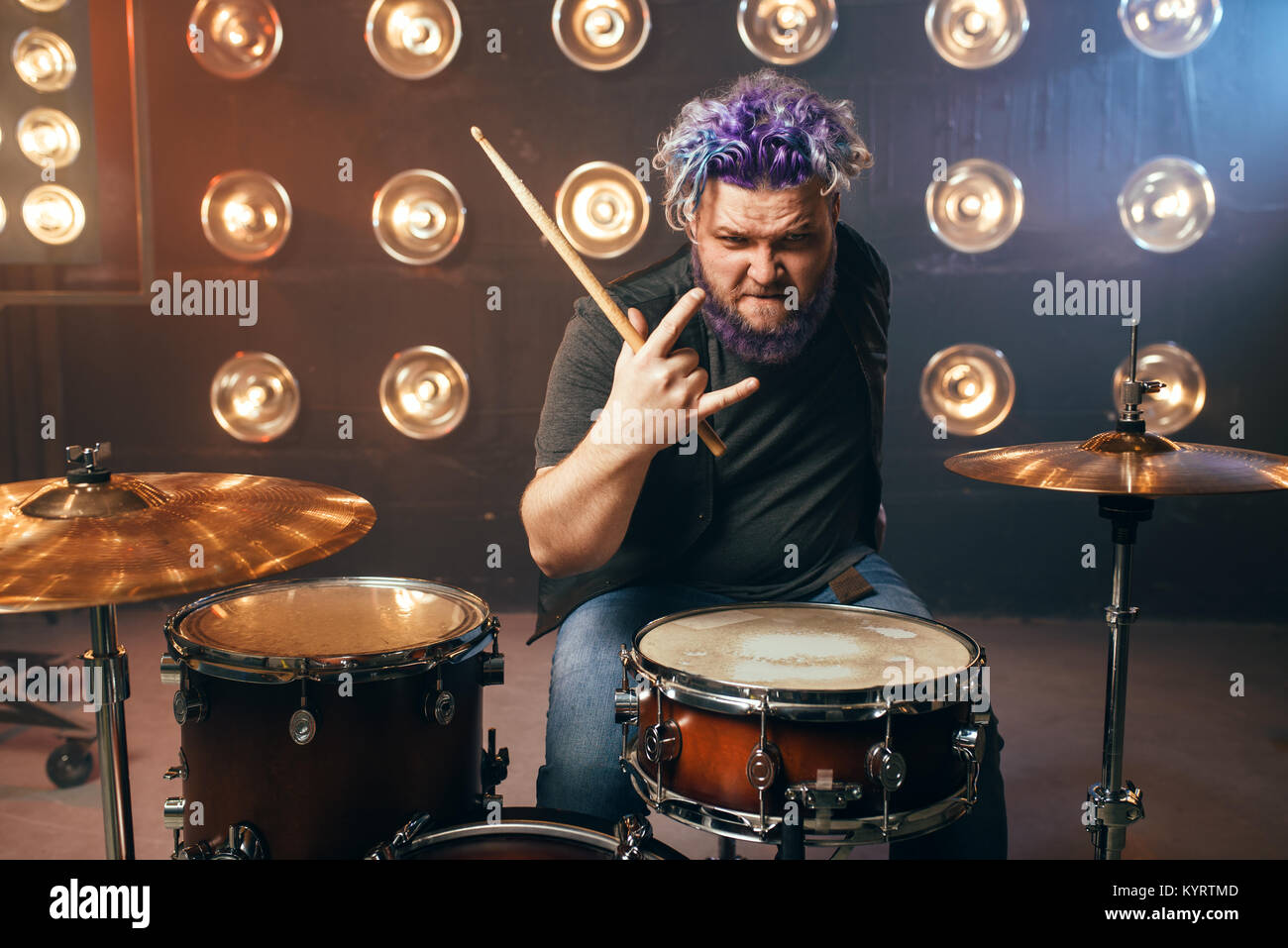 Bearded drummer with colorful hair, rock performer on the stage with ...